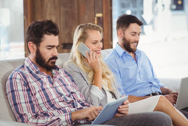 Woman Talking Over Phone while Colleagues Using Technologies Stock ...