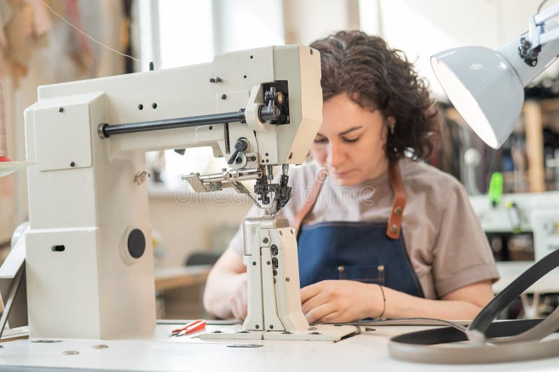 A Woman Tanner Sews a Leather Belt on a Sewing Machine. Stock Image ...
