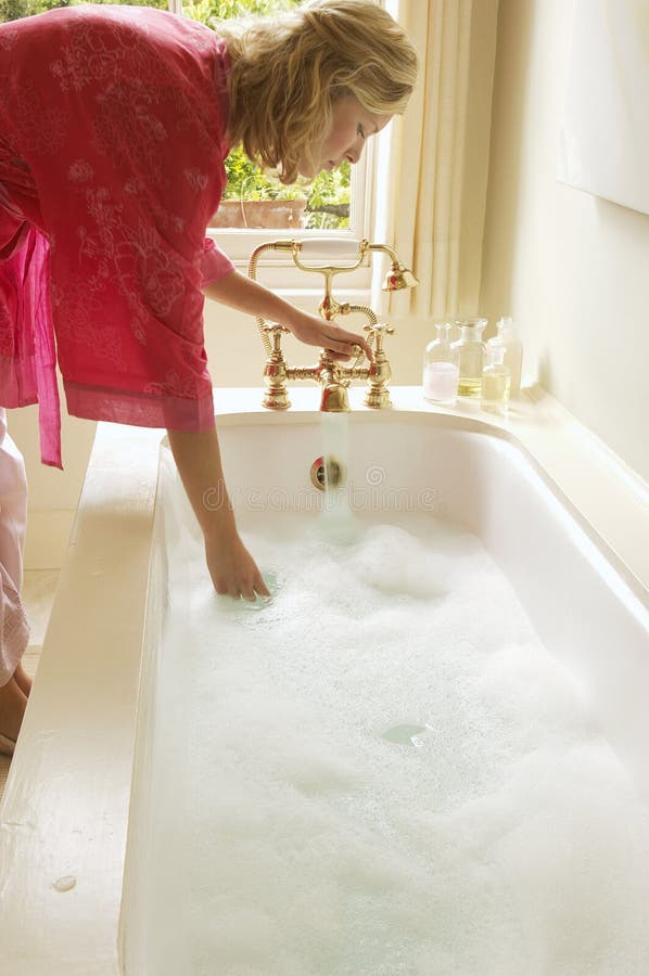 Woman Testing Water in Bathtub Filled with Bubbles Stock Image - Image ...