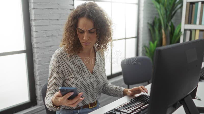 Woman Typing on a Computer in a Modern Office with a Worried Expression ...