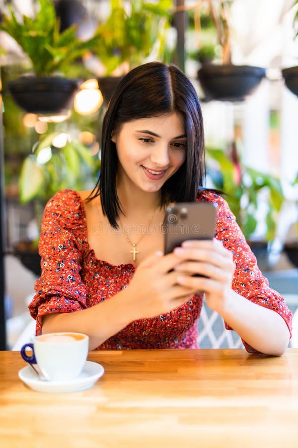 Woman Typing Text Message on Smart Phone in a Cafe. Young Woman Sitting ...