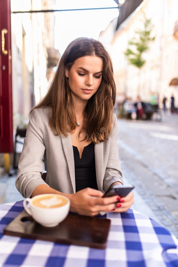 Young Woman Typing Text Message on Smart Phone in a Cafe. Young Woman ...