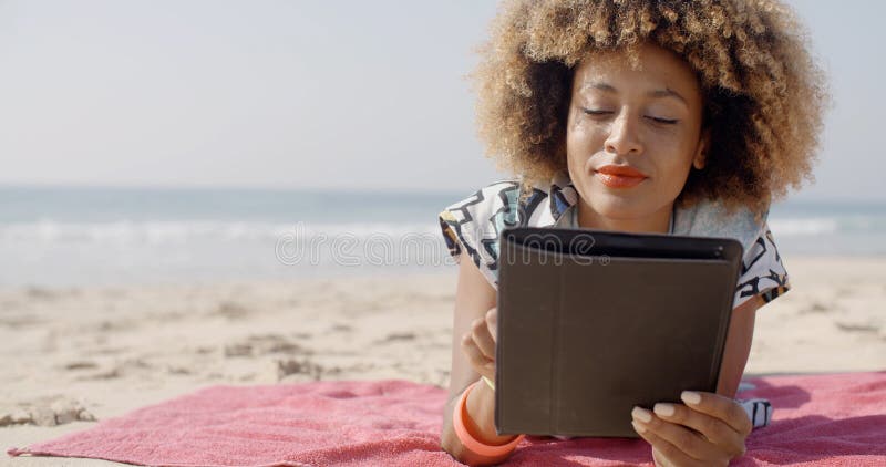 Woman Uses a Tablet on the Beach Stock Image - Image of lying, haircut ...