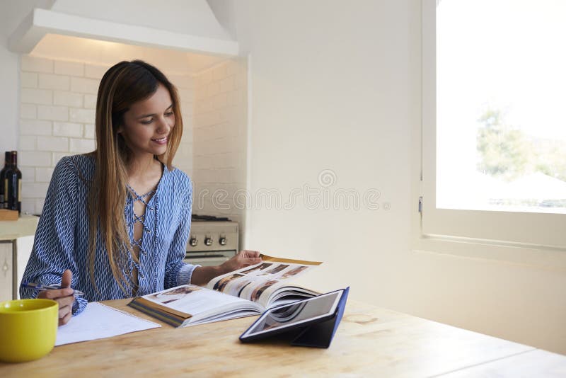 Woman Using Book and Tablet Writing in Kitchen, Close Up Stock Photo ...