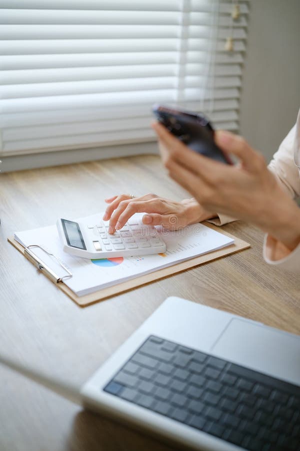 A Woman is Using a Calculator and a Cell Phone on a Desk Stock Photo ...