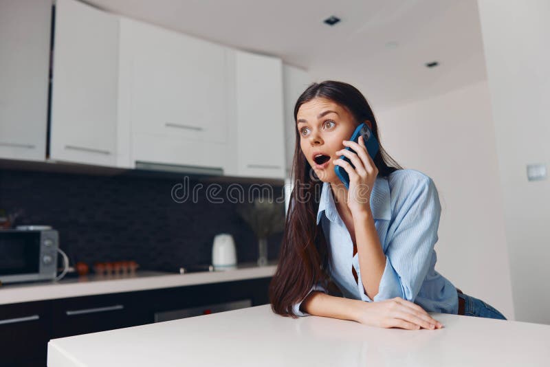 Woman Using Cell Phone at Kitchen Table, Casual Conversation in Modern ...