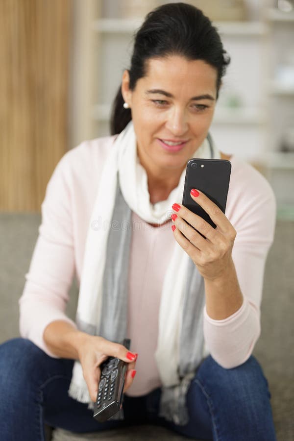 Woman Using Cellphone and Holding Remote Control Stock Image - Image of ...