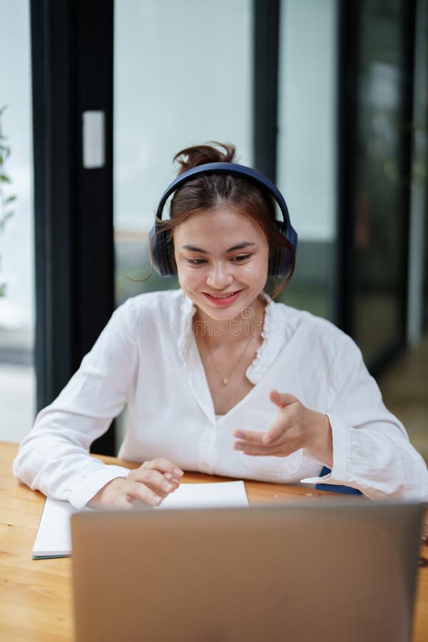 Woman Using a Computer and Earphone during a Video Conference Stock ...