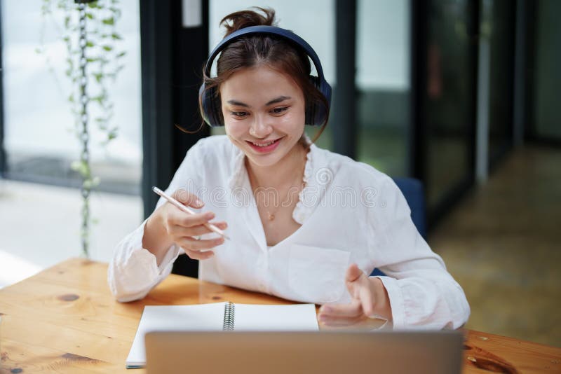 Woman Using a Computer and Earphone during a Video Conference Stock ...