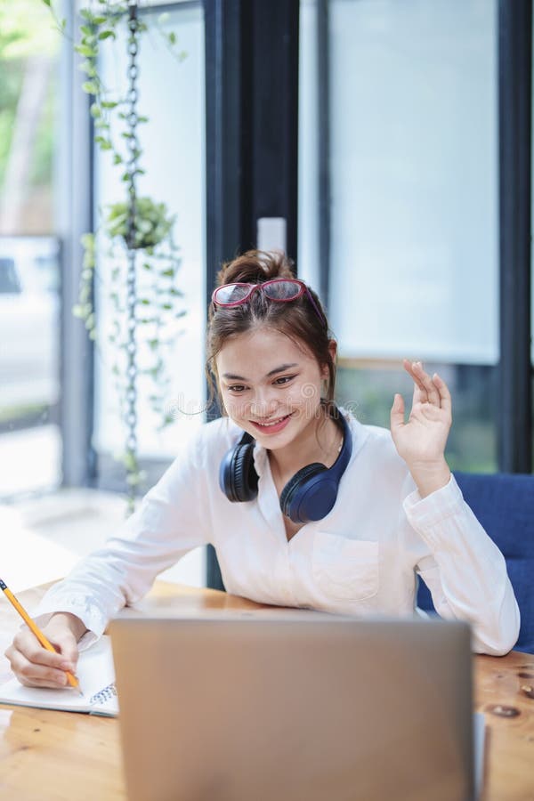 Woman Using a Computer and a Notebook during a Video Conference Stock ...