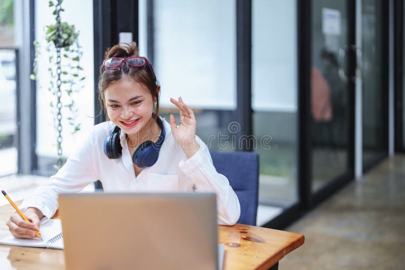 Woman Using a Computer and a Notebook during a Video Conference Stock ...