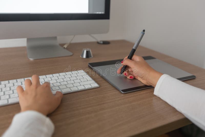 A Woman Using a Drawing Screen with a Pen, One Hand on the Keyboard ...