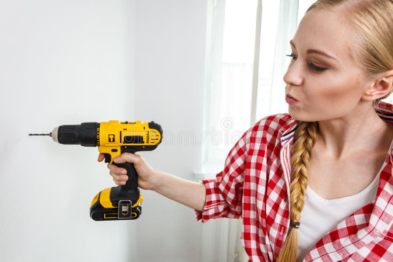 Woman using drill on wall stock photo. Image of home - 155233236