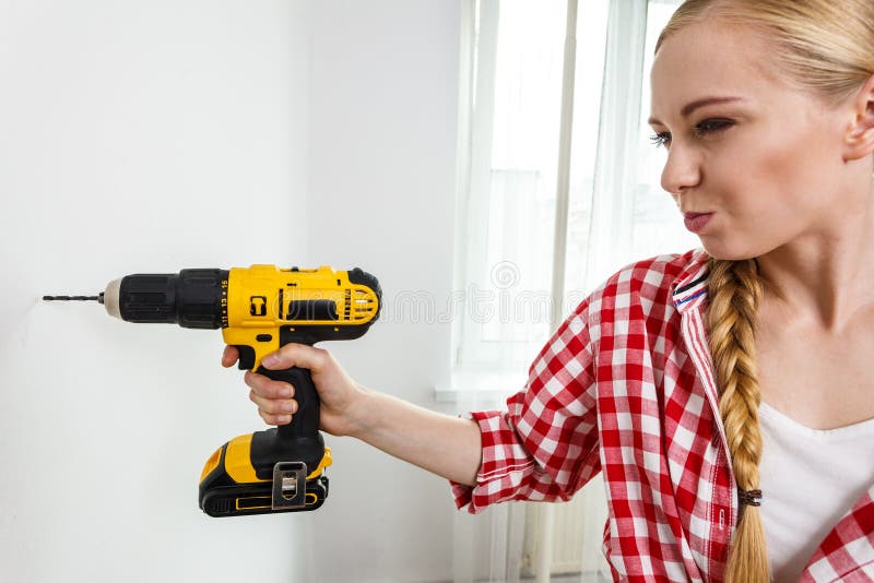 Woman using drill on wall stock photo. Image of equipment - 162587200