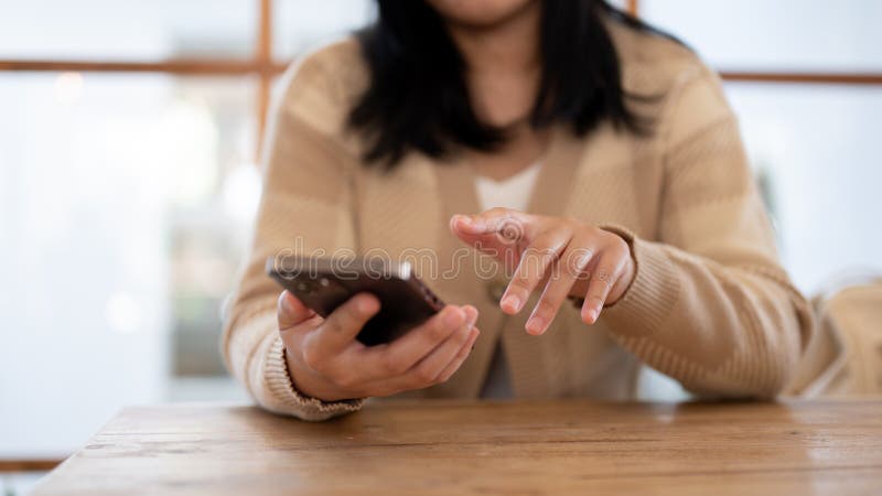 A Woman Using Her Smartphone while Sitting at a Table Indoors. People ...