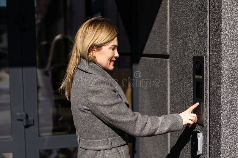 Happy Woman Ringing on Doorbell at Building Entrance. Using Intercom ...