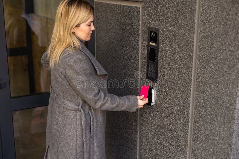 Woman Using Intercom at Building Entrance. Stock Image - Image of ...