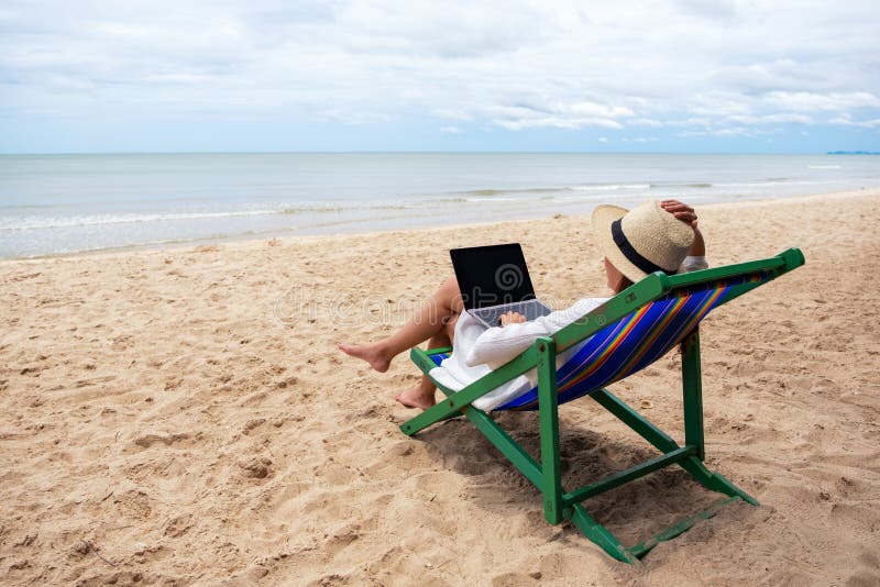 A Woman Using Laptop Computer while Lying Down on a Beach Chair Stock ...