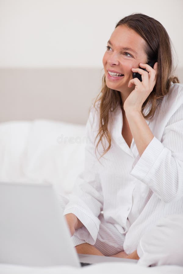 A Woman Using a Laptop while Making a Phone Call Stock Photo - Image of ...