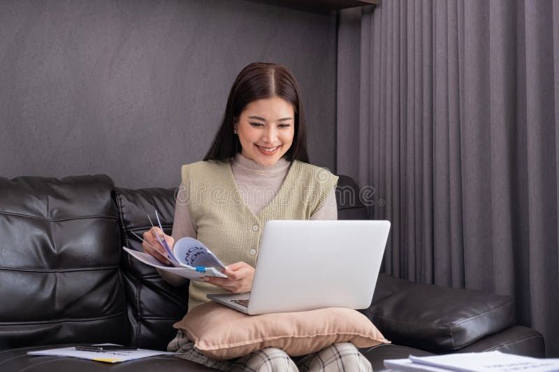 Woman Using Laptop and Reading Document on Sofa. Concept of ...