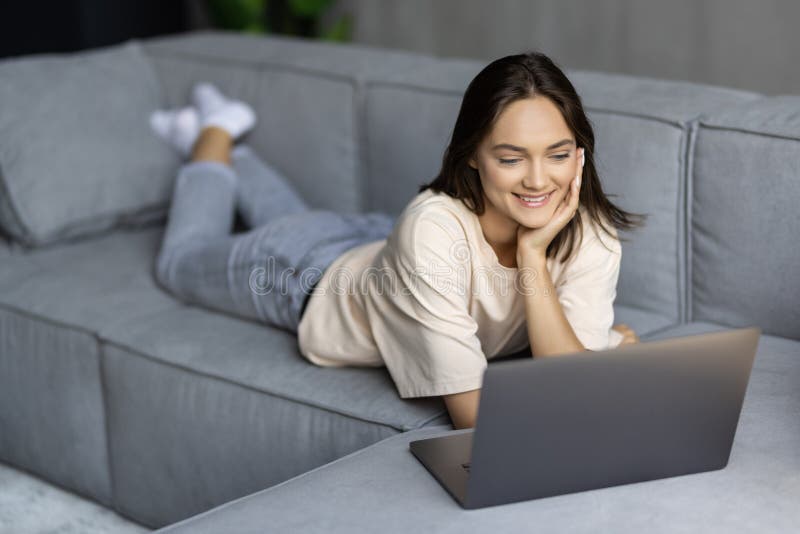 Young Woman Using a Laptop while Relaxing on the Couch Stock Image ...
