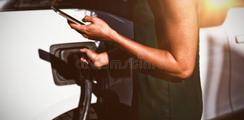 Woman Using Mobile Phone while Charging Electric Car at Charging ...