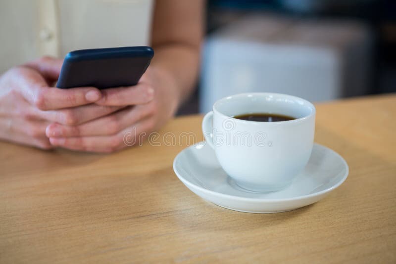 Woman Using Mobile Phone and a Coffee Cup on the Table in Coffee Shop ...