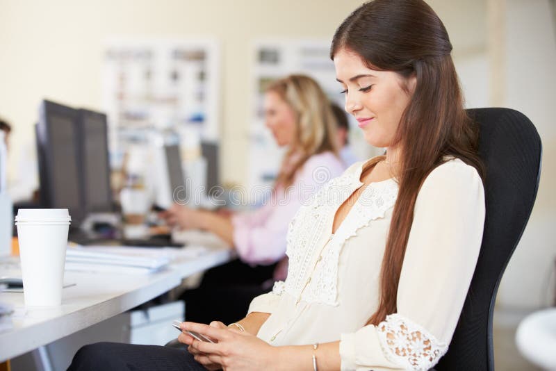 Woman Using Mobile Phone at Desk in Busy Creative Office Stock Image ...