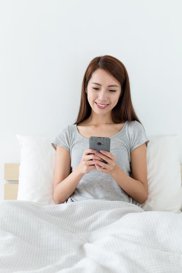 Woman Using Mobile Phone and Sitting on Bed Stock Photo - Image of ...