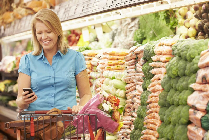 Woman Using Mobile Phone In Supermarket Stock Photo - Image of indoors ...