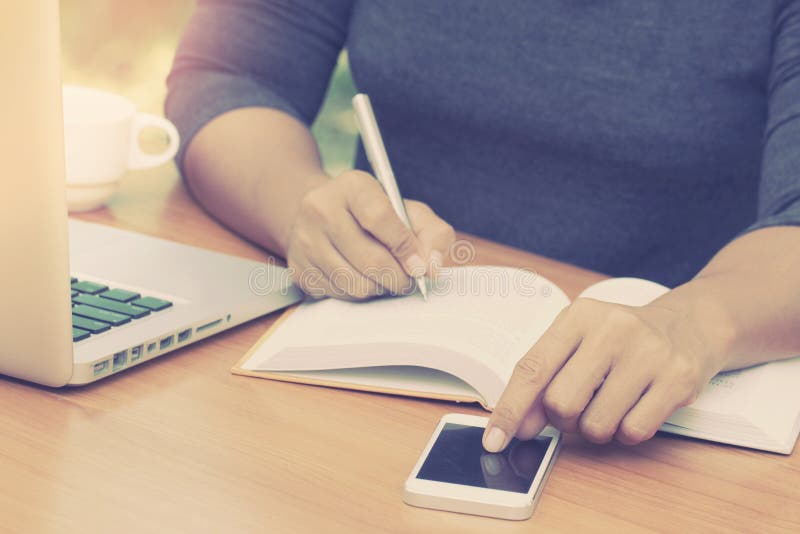 Woman Using Mobile Smartphone and Writing on Notebook at the Off Stock ...