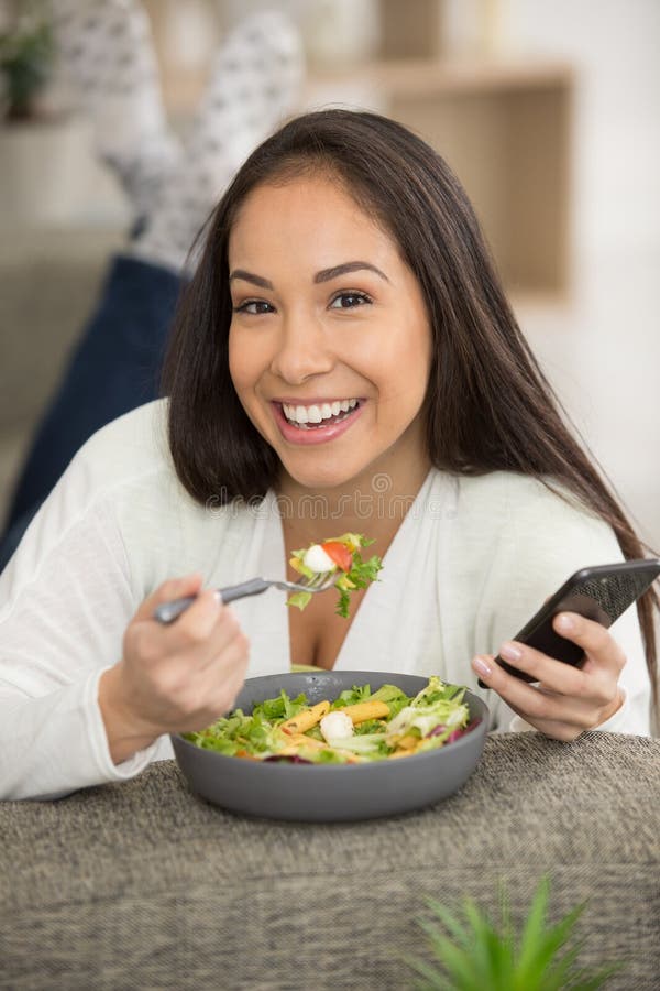 Woman Using Smartphone while Eating Salad Meal on Sofa Stock Photo ...