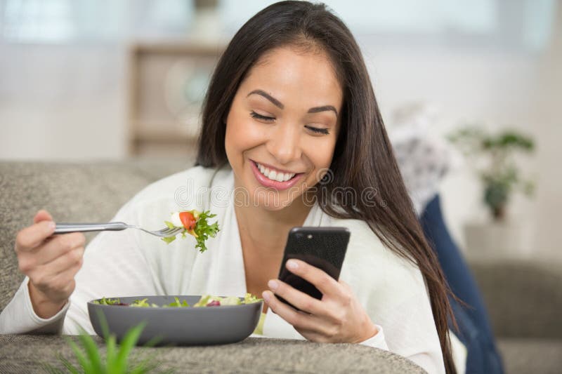 Woman Using Smartphone while Eating Salad Meal on Sofa Stock Image ...