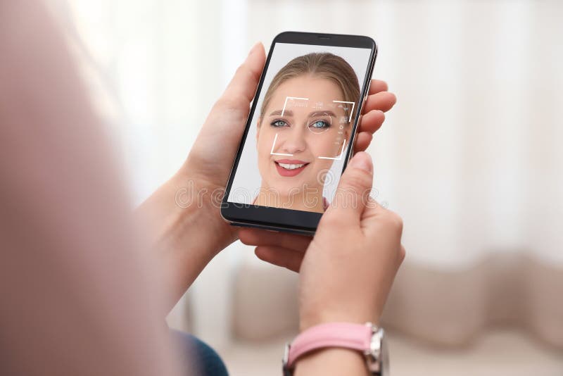 Woman Using Smartphone With Facial Recognition System Indoors