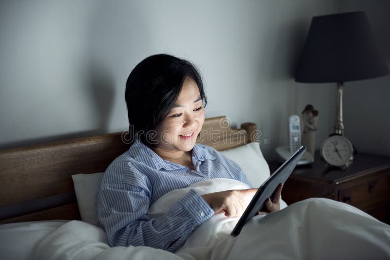 A Woman Using a Tablet in Bed Stock Photo - Image of device ...