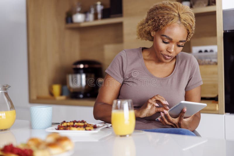 Woman Using Tablet Computer while Eating Breakfast at Home Stock Photo ...