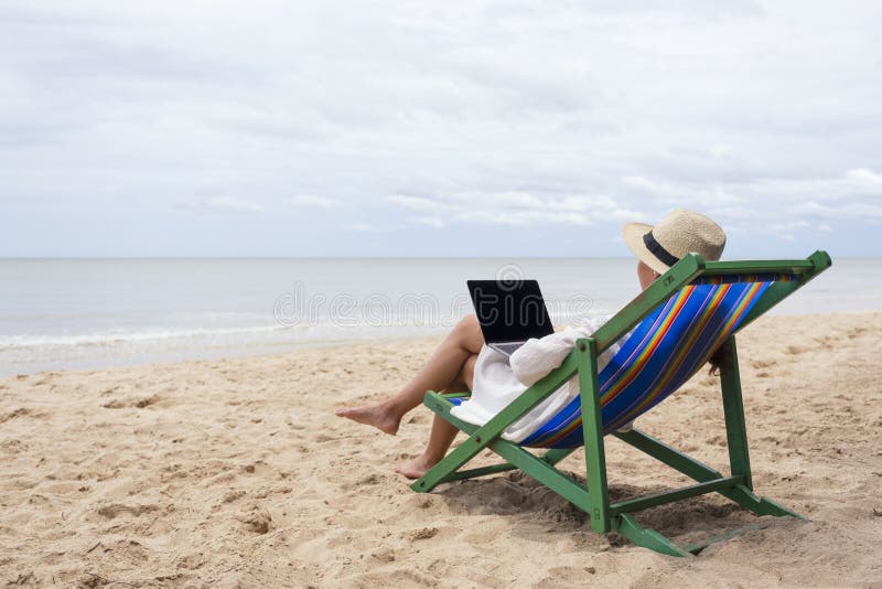 A Woman Using and Typing on Laptop Computer on a Beach Chair Stock ...