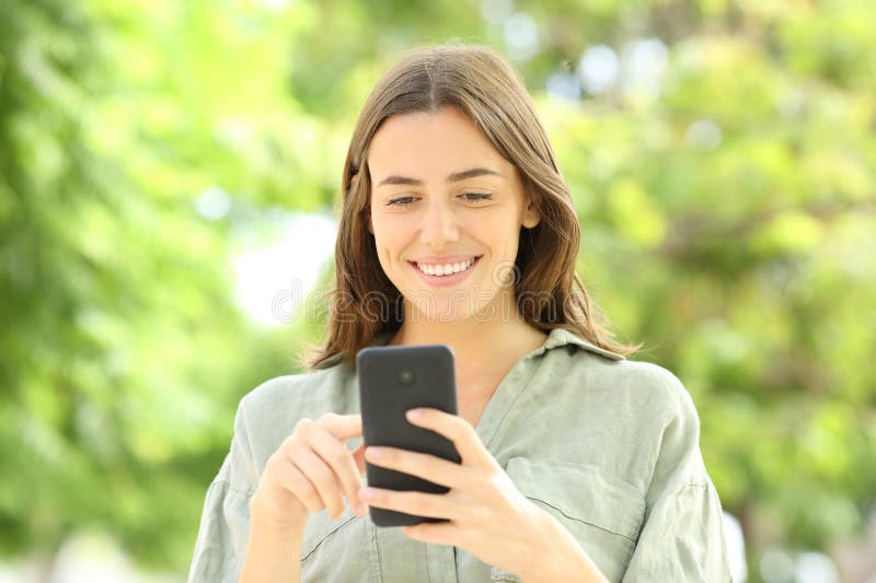 Woman Walking Using Cell Phone in a Park Stock Photo - Image of ...