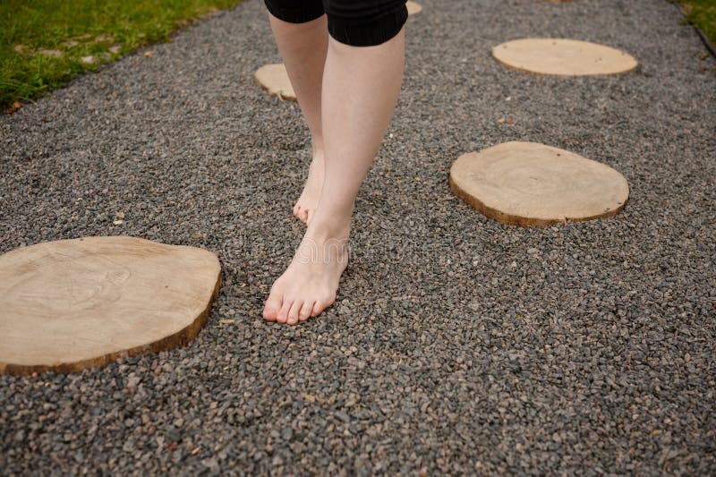 Woman Walks Barefoot Along A Tactile Massage Path Made Of Small Stones