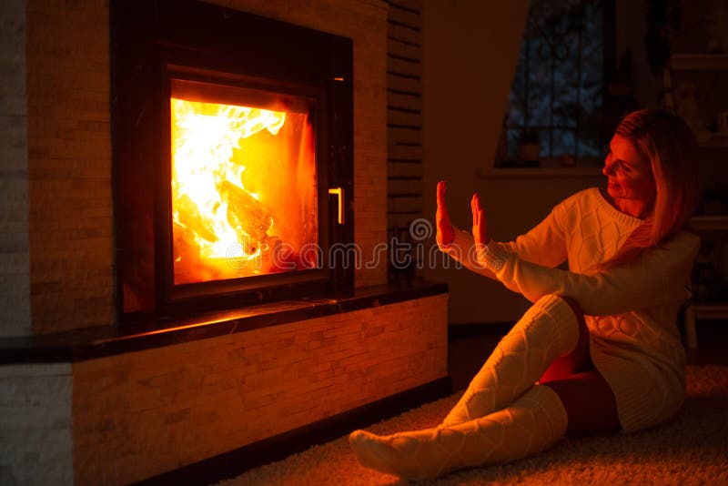 A Woman is Warming Her Hands by the Burning Fireplace. a Winter Evening ...