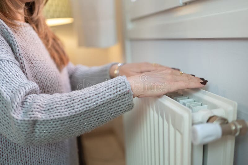 Woman Warming Her Hands in a Radiator because of the Cold of Winter ...