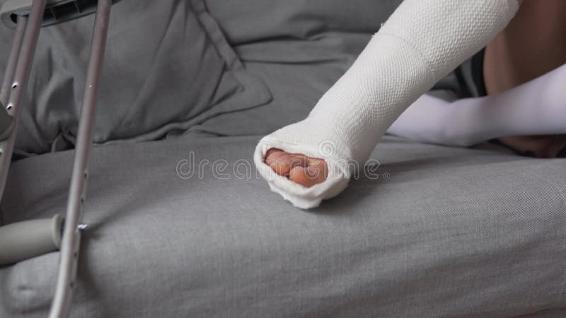 A Woman with Plaster on Her Feet Gets Out of Bed with the Help of ...