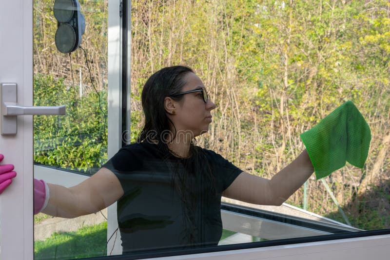 A Woman Washes a Window from the Outside, Using a Rag and Rubber Gloves ...
