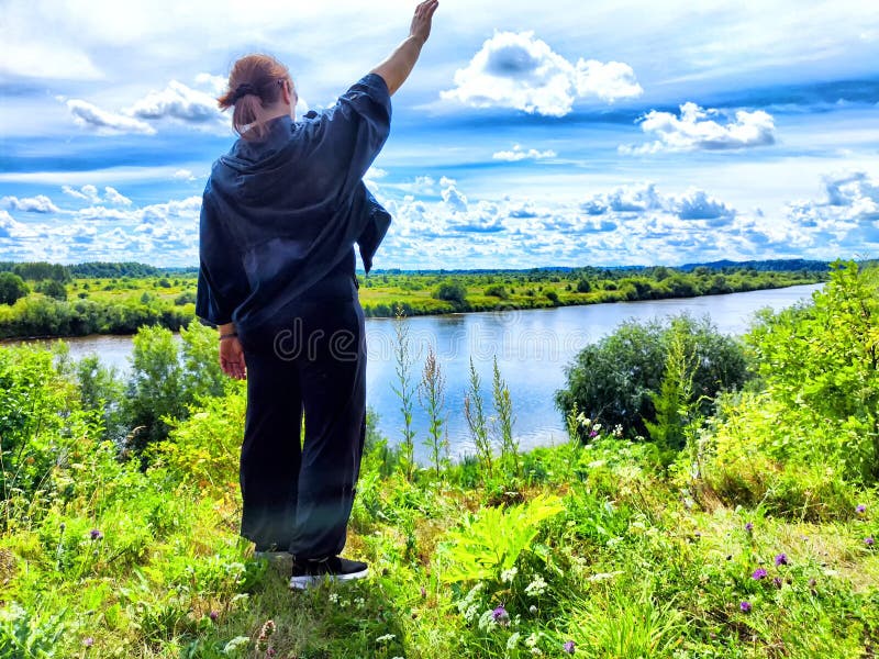A Woman Waves from a Hilltop, Overlooking a River Surrounded by Lush ...
