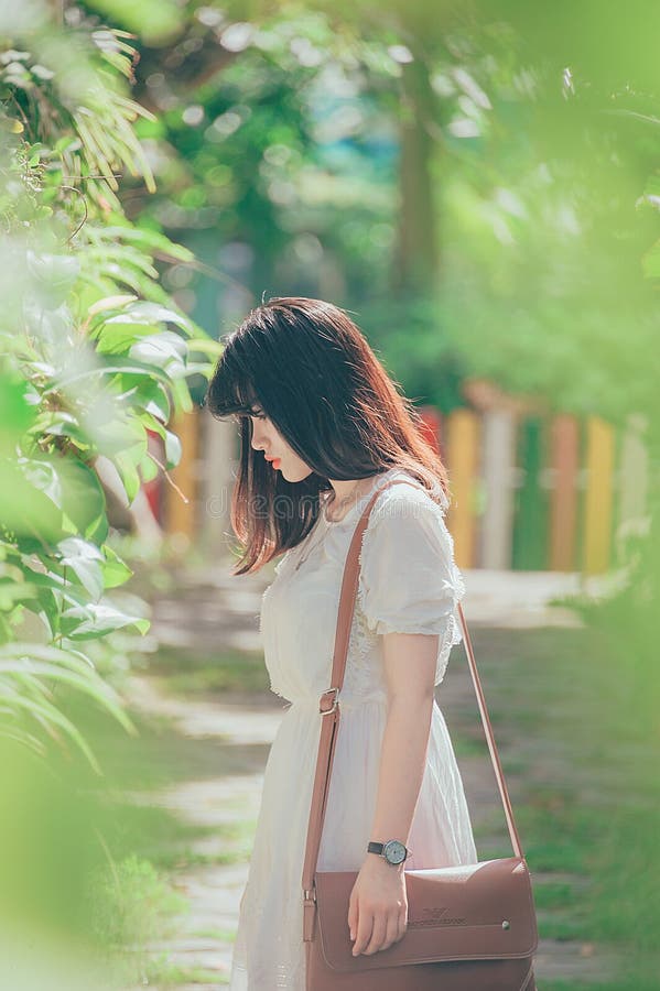 Woman Wearing White Crew Neck Short Sleeved Dress Standing Beside Green