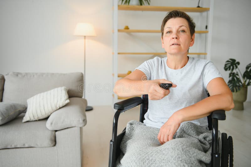 Woman in Wheelchair Uses a Tv Remote Control. Stock Image - Image of ...