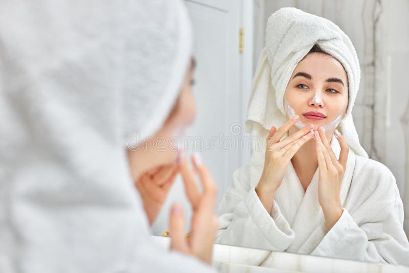 Woman In White Bathrobes Applying Apply Facial Cream Stock Image