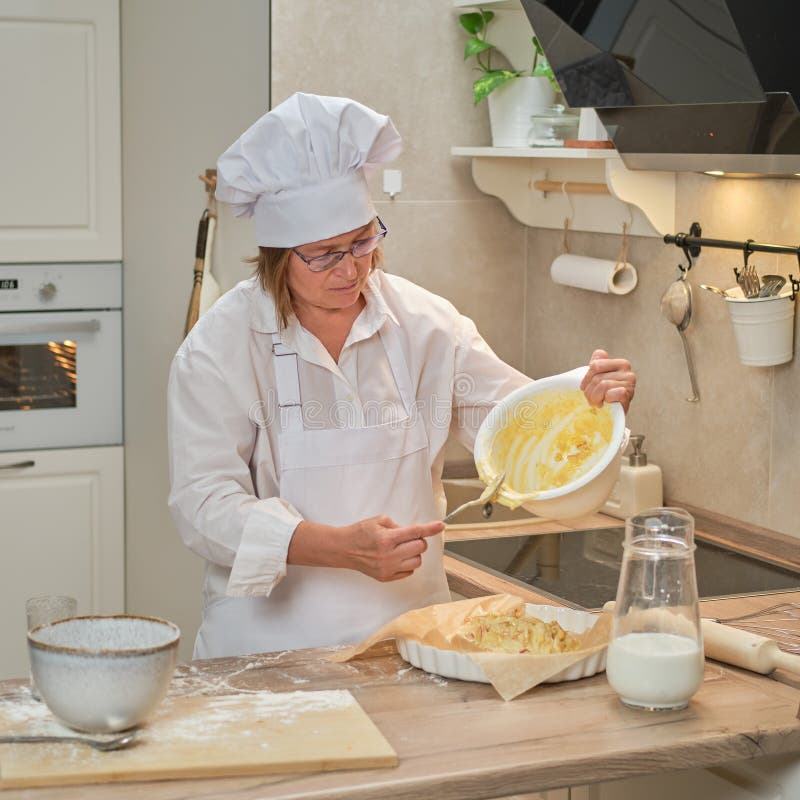 An Woman in White Chef Clothes Cooking Pie in a Beige Kitchen Stock ...