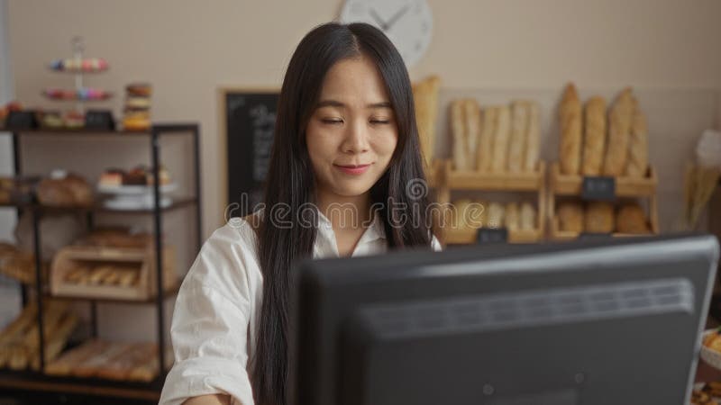 Woman Working in Bakery Surrounded by Various Bread Types while Using ...