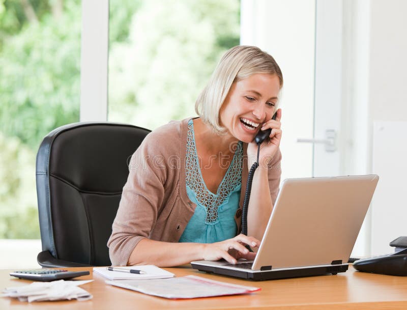Woman Working on Her Computer while she is Phoning Stock Photo - Image ...